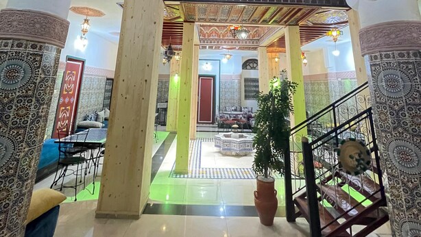 Um interior espaçoso com área central aberta, escada e varanda com grades decorativas.