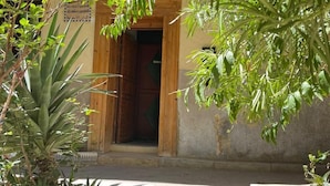 Um pátio com uma porta de madeira, degraus que levam a um edifício e vasos com plantas.