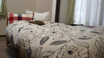 Um quarto com colcha florida, travesseiro quadriculado e mesa de cabeceira com abajur.
