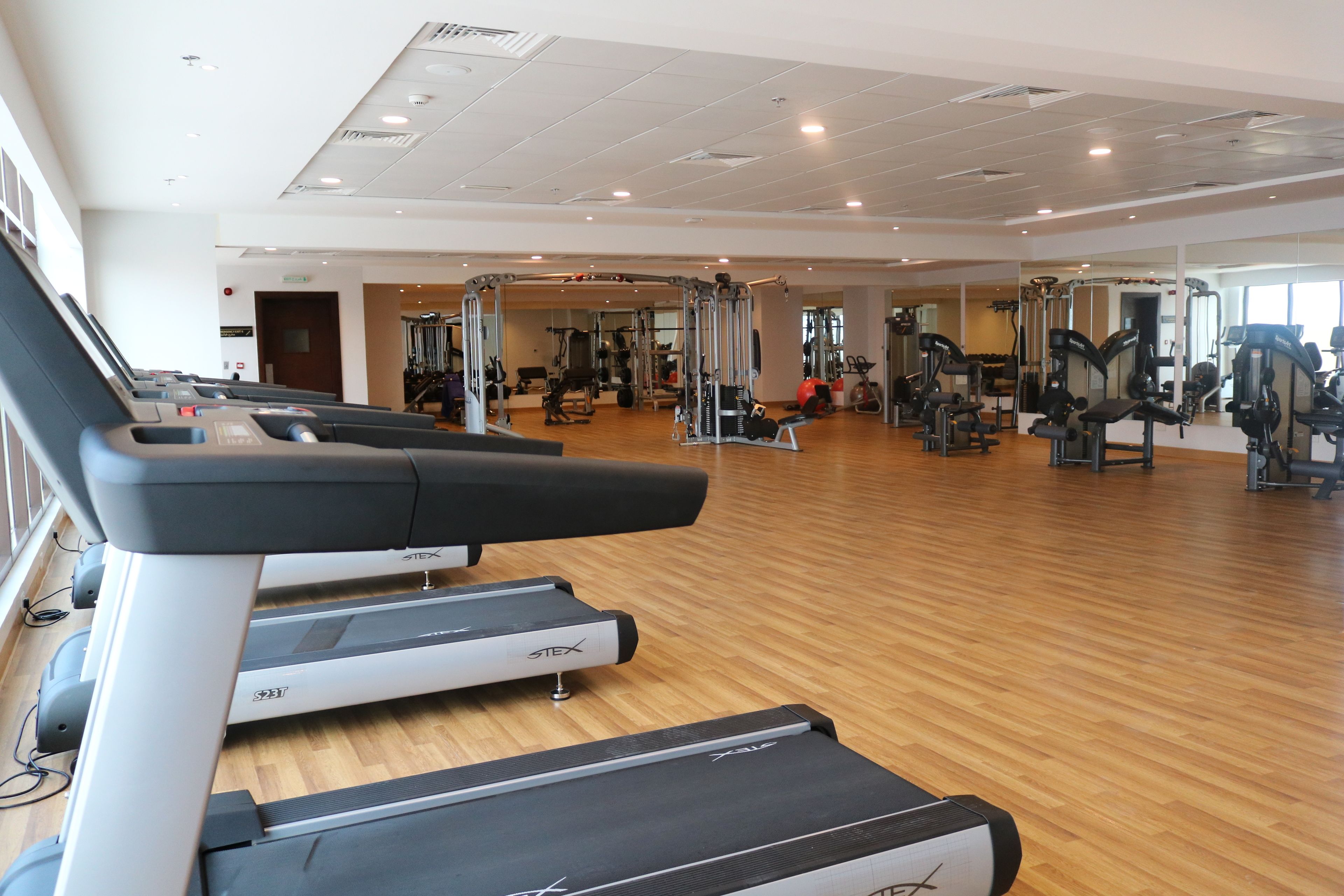 Academia com esteiras, aparelhos de musculação e um espelho grande.