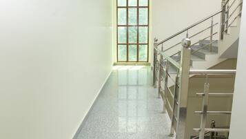 Um corredor limpo e bem iluminado com uma porta de vidro que dá para uma varanda, corrimão de metal e escadas.