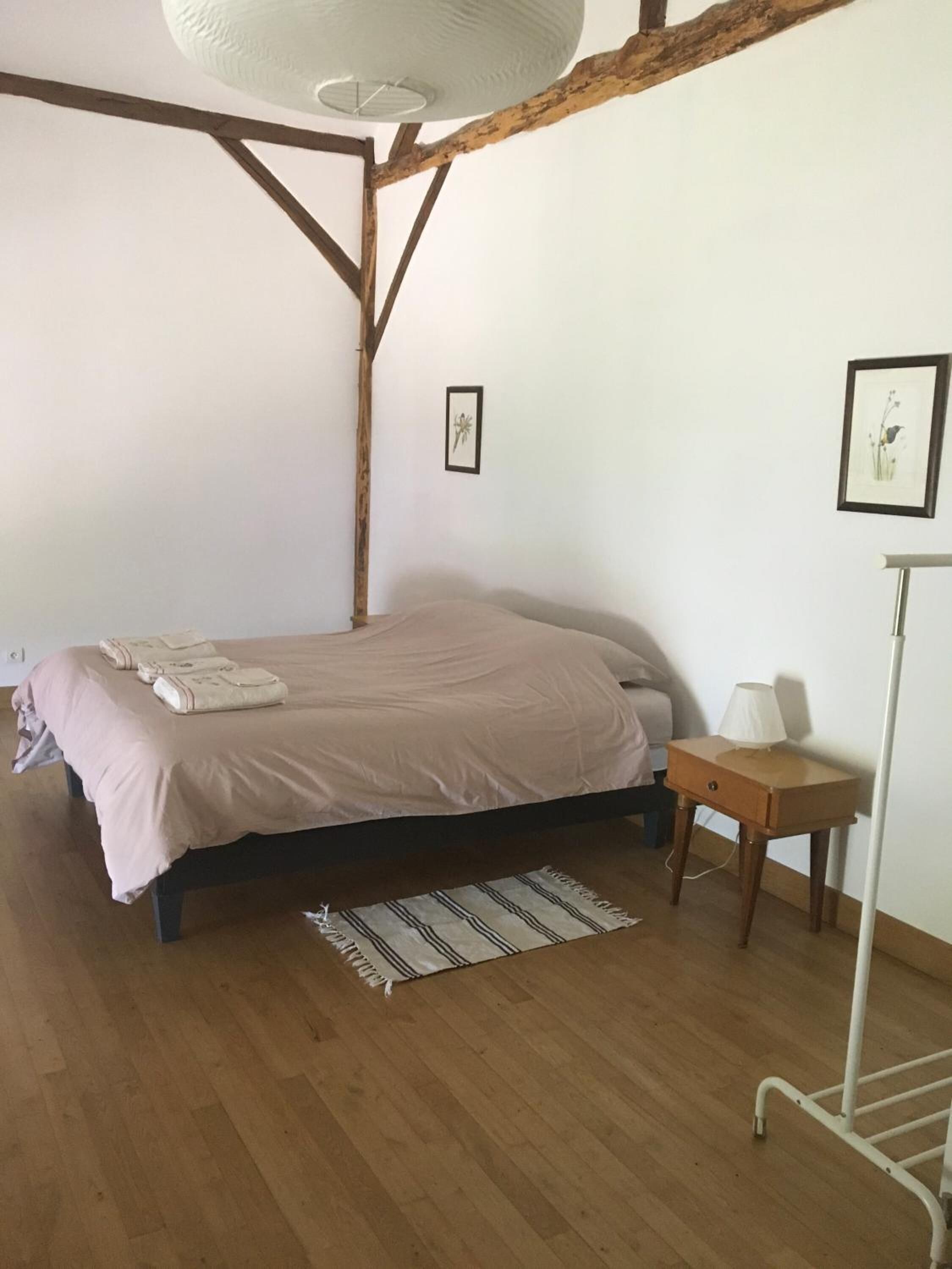 Quarto com cama, mesa de cabeceira, abajur e tapete.