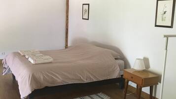 Quarto com cama, mesa de cabeceira, abajur e tapete.