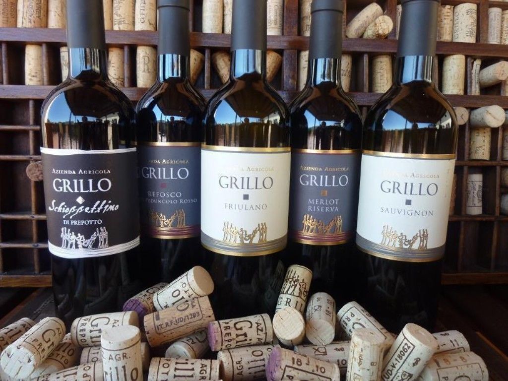 Quatro garrafas de vinho Grillo com rolhas espalhadas.