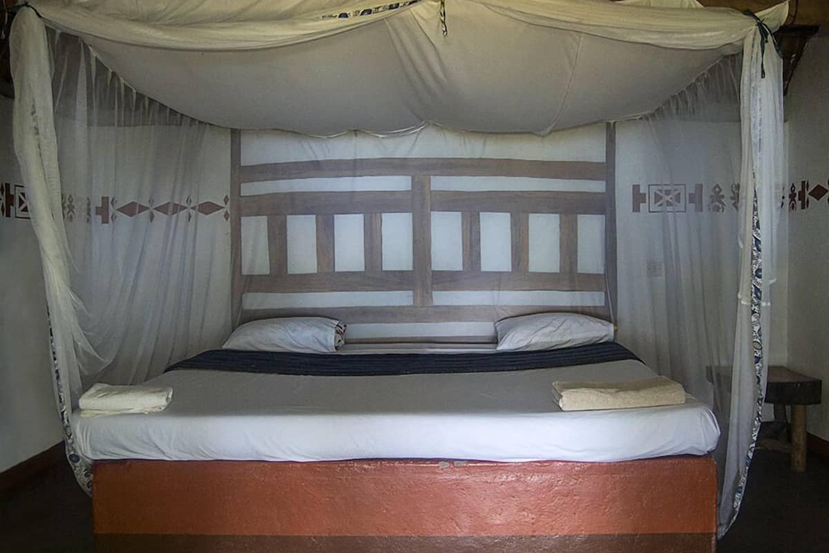 Cama com dossel, almofadas e manta.