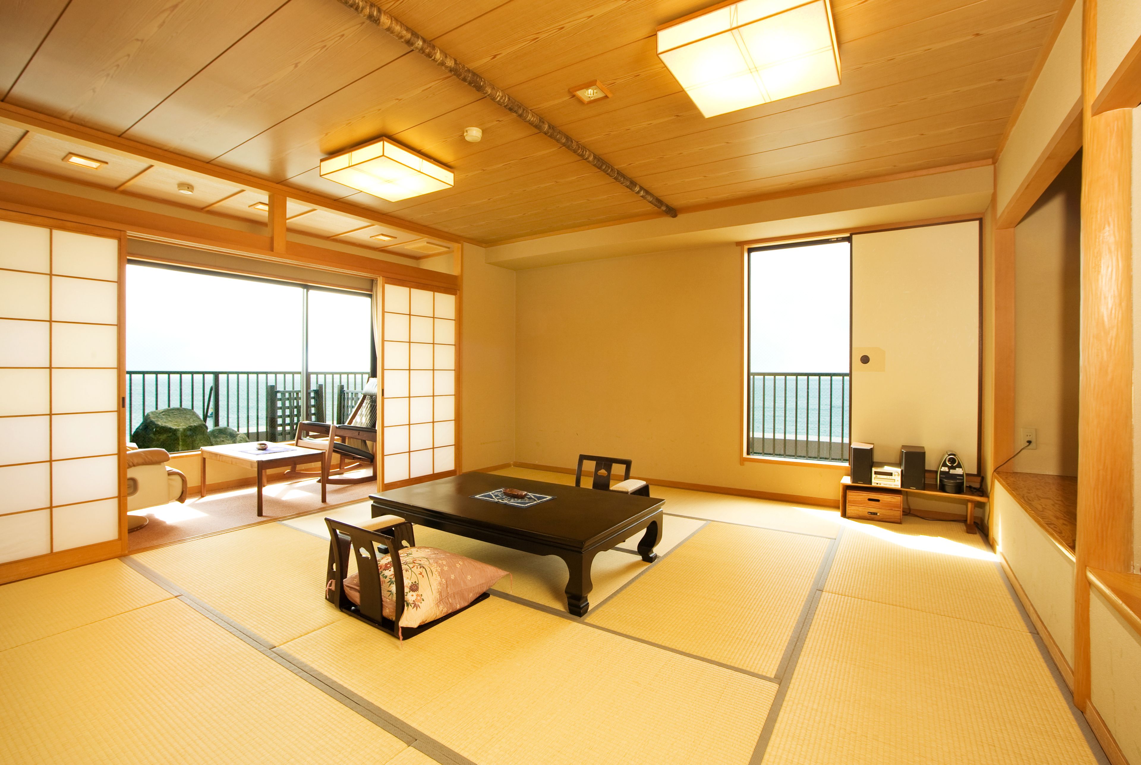 Um quarto japonês tradicional com tatames, uma mesa baixa com cadeiras, portas deslizantes e vista para a cidade.