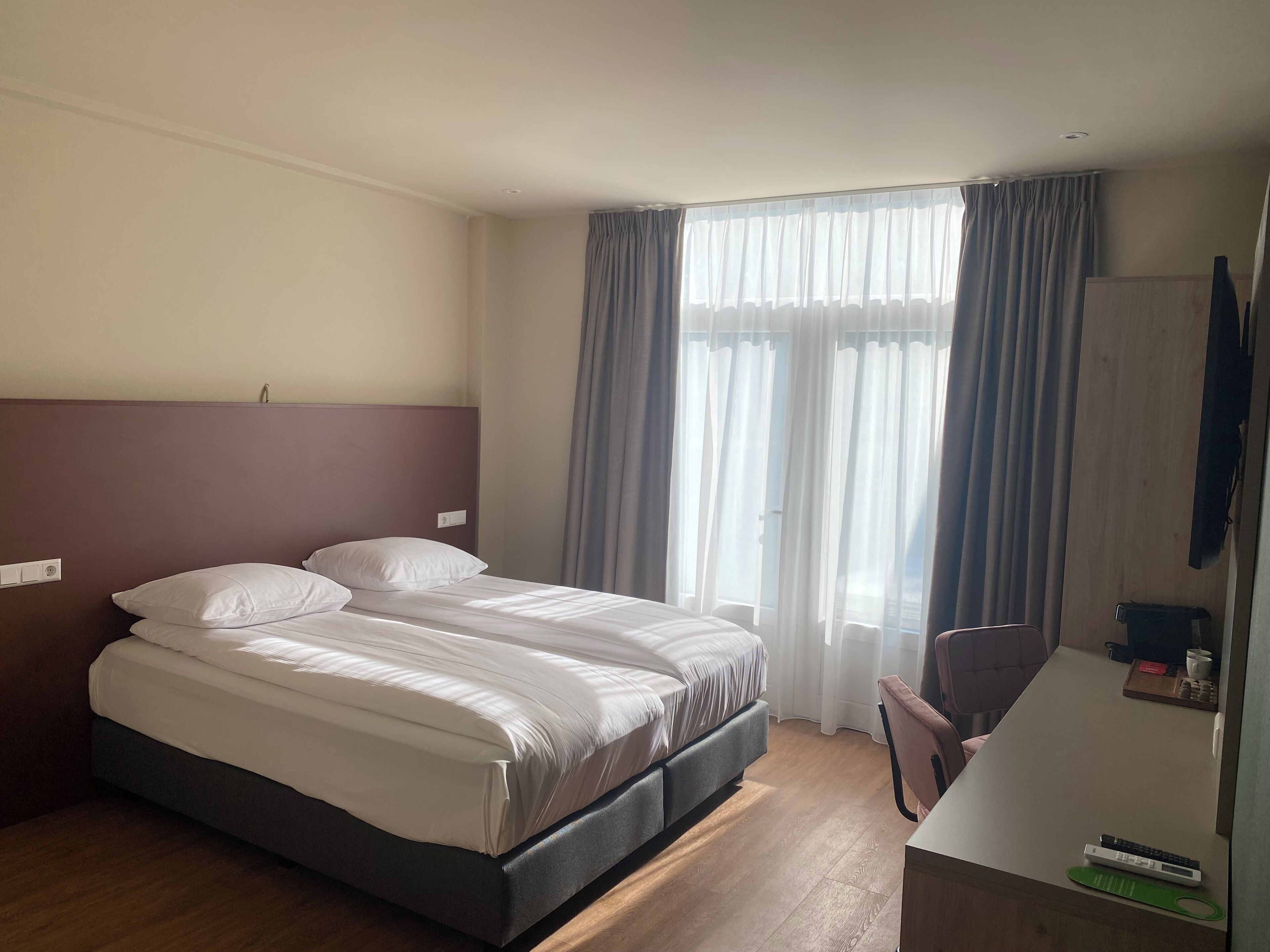 Quarto de hotel com uma cama, uma escrivaninha e uma cadeira.
