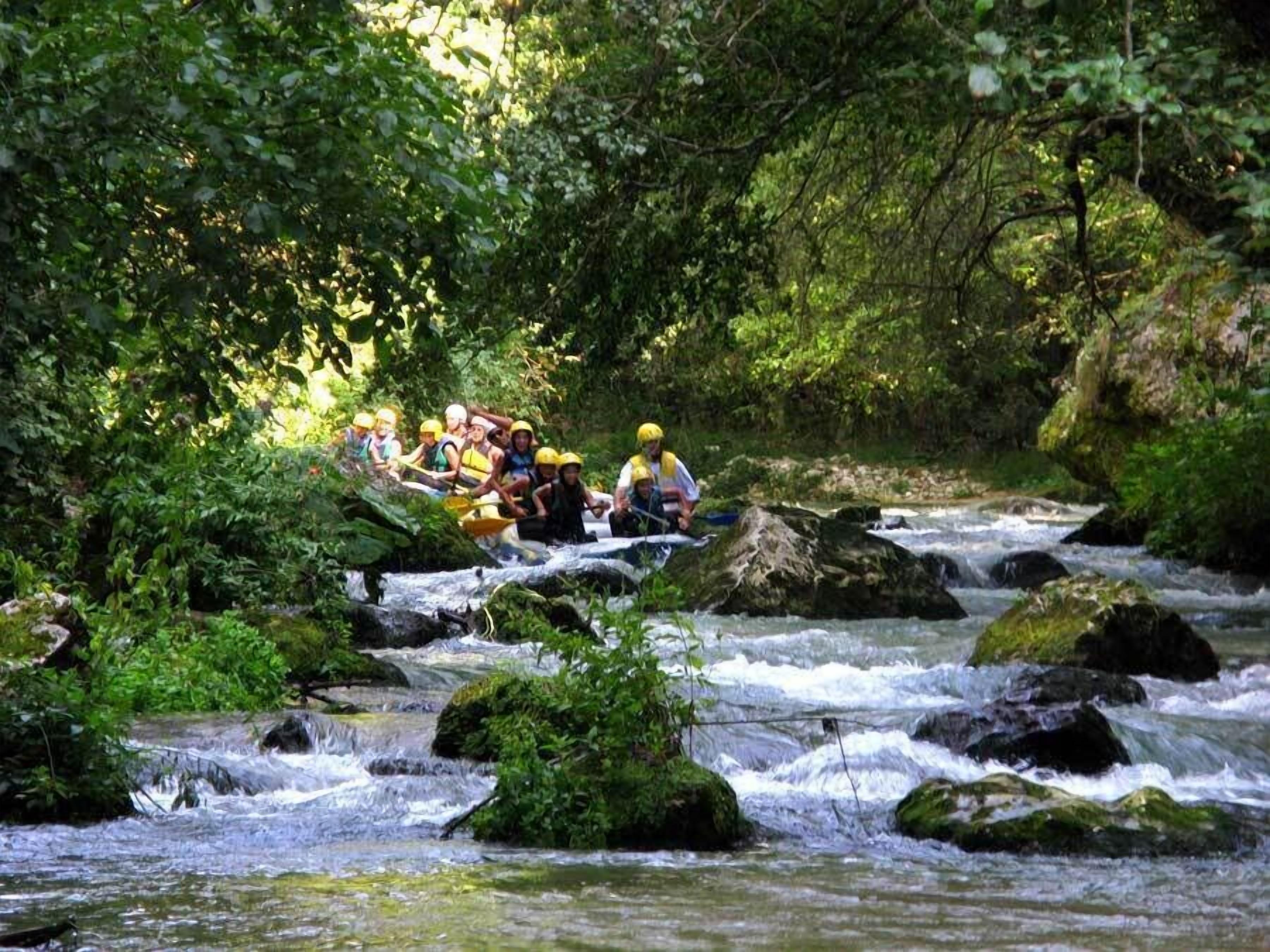 Um grupo de pessoas fazendo rafting em um rio, cercado por vegetação densa.