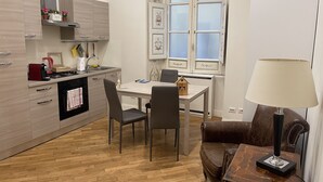 Uma cozinha compacta com eletrodomésticos modernos, um espaço de refeições com duas cadeiras e uma mesa pequena.