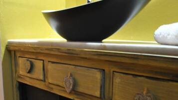 Casa de banho com lavatório preto, toucador de madeira com puxadores em forma de coração e toalhas dobradas com cuidado.