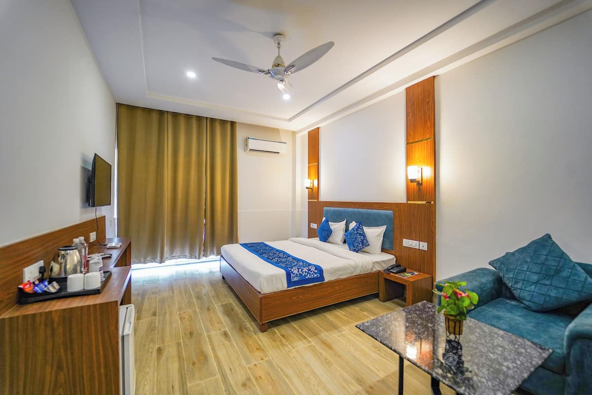 Quarto de hotel com cama, mesa de cabeceira, área de estar com sofá e mesa de centro.