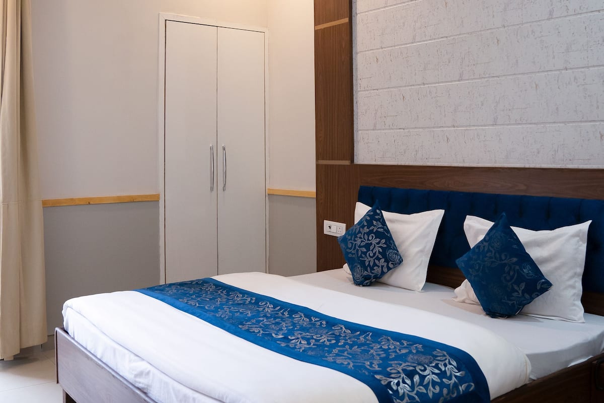 Quarto com cama, guarda-roupa, ar condicionado e ventoinha no teto.