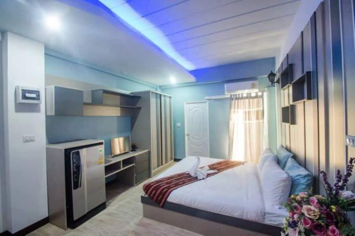 Quarto de hotel moderno com cama, secretária embutida e guarda-roupa.