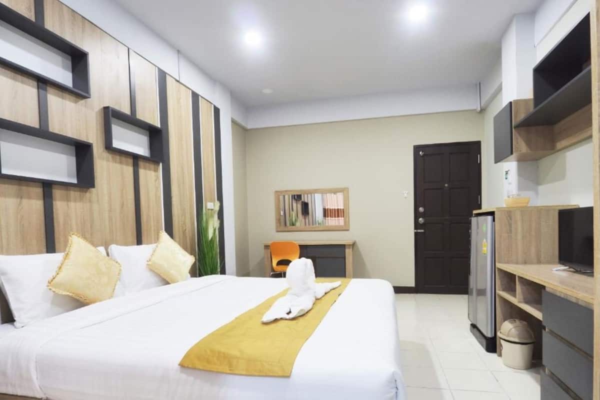 Quarto de hotel com cama, escrivaninha, cadeira, guarda-roupa e porta.