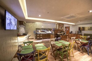 Restaurante com balcão, área de estar e uma televisão exibindo um programa.