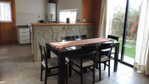 Uma cozinha com bancada de pedra, armários de madeira e uma área de refeições com mesa e cadeiras.