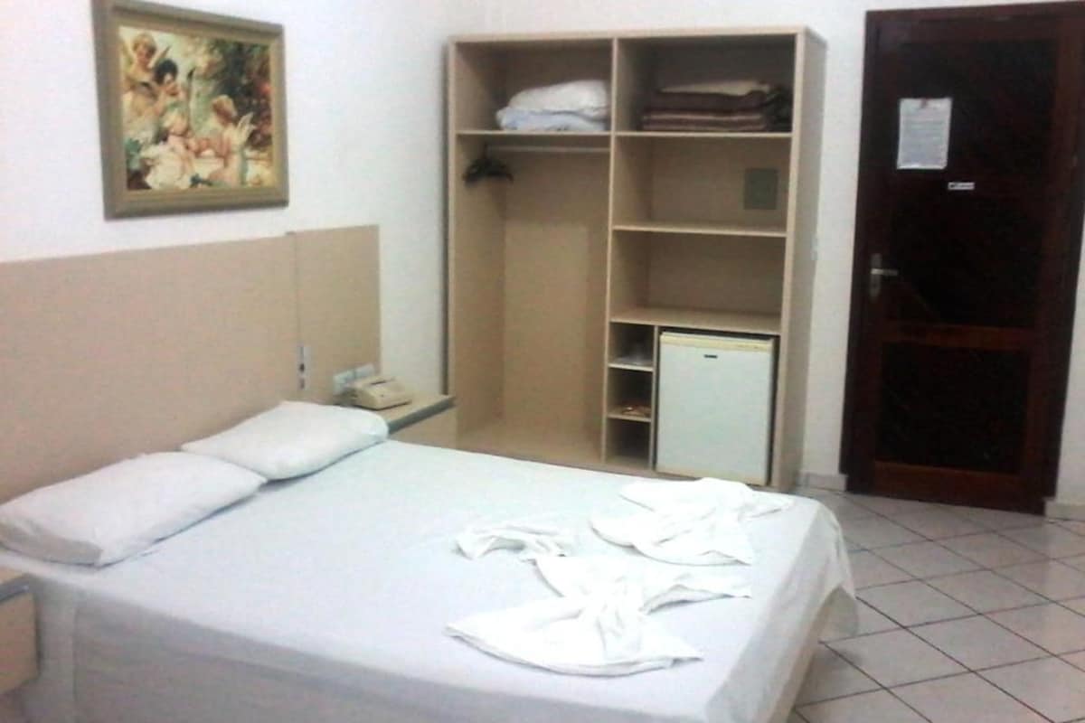 Um quarto com cama, guarda-roupa e escrivaninha.