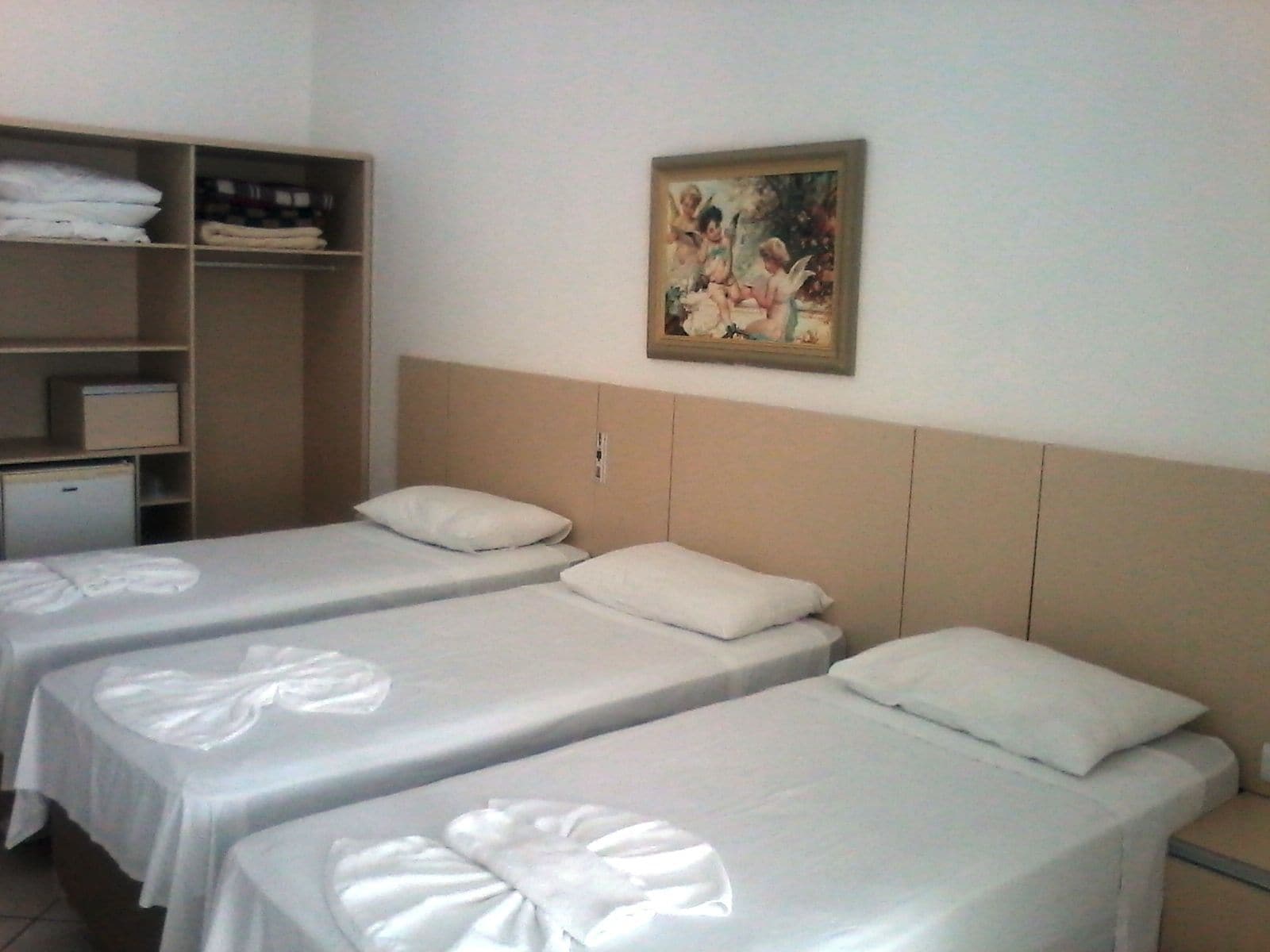 Quarto de hotel com duas camas de solteiro, uma secretária pequena e um guarda-roupa.