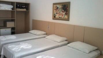 Quarto de hotel com duas camas de solteiro, uma secretária pequena e um guarda-roupa.