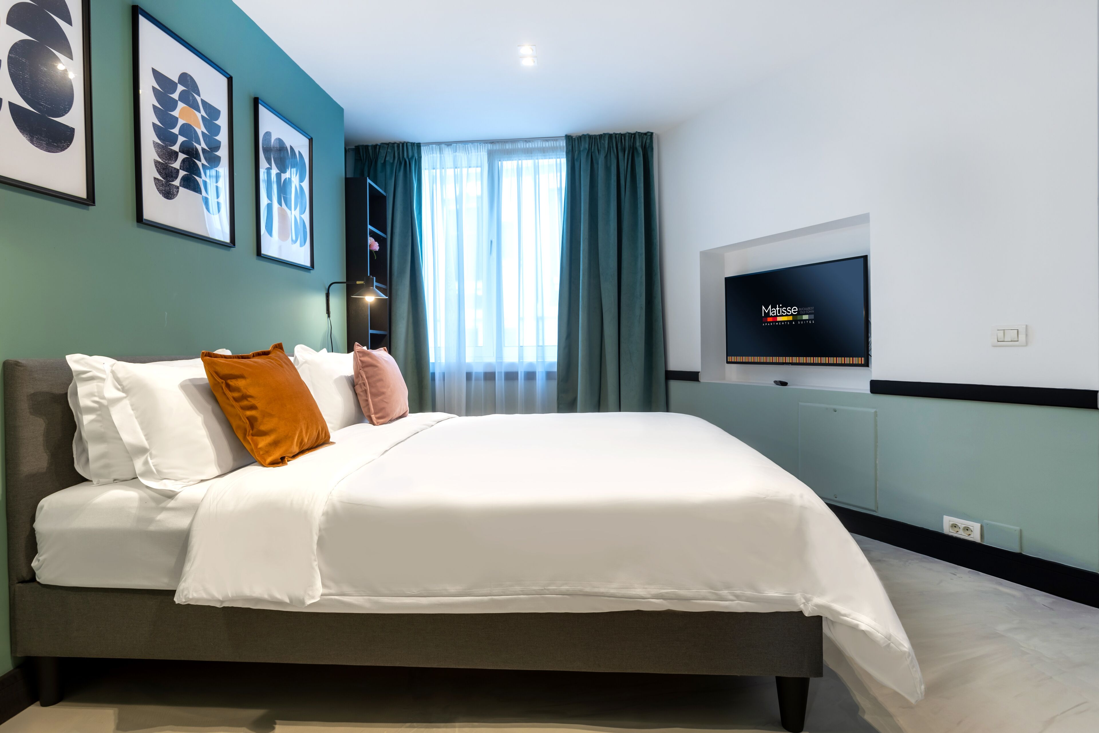 Quarto de hotel moderno com uma cama grande, TV de tela plana e arte abstrata nas paredes.