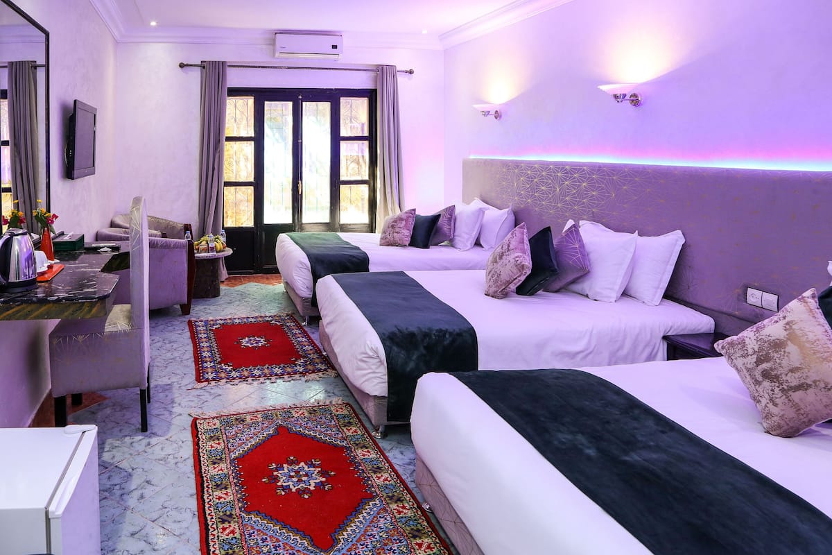 Quarto de hotel com duas camas, uma mesa e uma televisão.