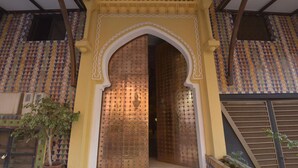 Uma entrada tradicional com uma porta grande e ricamente decorada e um arco ornamental.