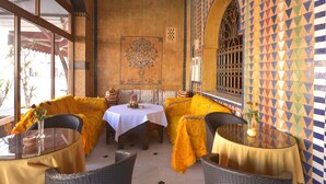 Uma área de jantar acolhedora com uma mesa e cadeiras, uma parede decorativa com padrões geométricos e uma janela grande com vista.