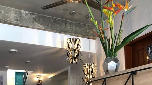 Um lobby moderno com escada, poltrona amarela e iluminação decorativa.