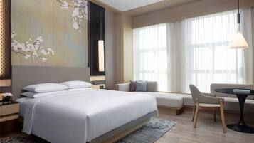 Quarto de hotel moderno com uma cama grande, um sofá, uma cadeira e uma pequena mesa.