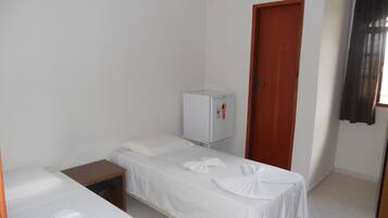 Quarto pequeno e limpo com uma cama de solteiro, mesa de cabeceira, armário pequeno e uma porta.