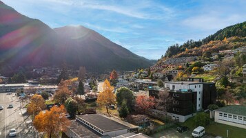 Uma cidade com uma mistura de edifícios modernos e tradicionais, uma montanha ao fundo e árvores com folhagem outonal.