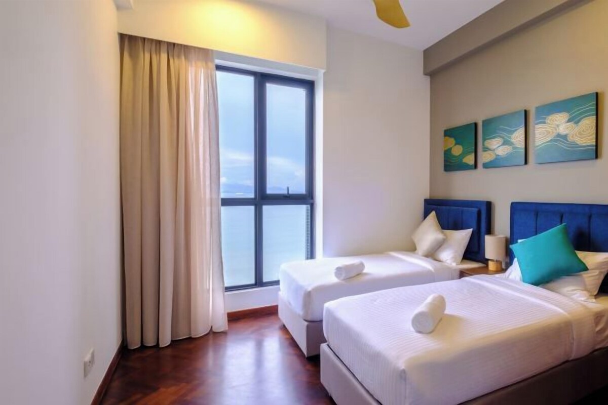 Quarto de hotel com duas camas, uma janela grande com cortinas e obras de arte na parede.
