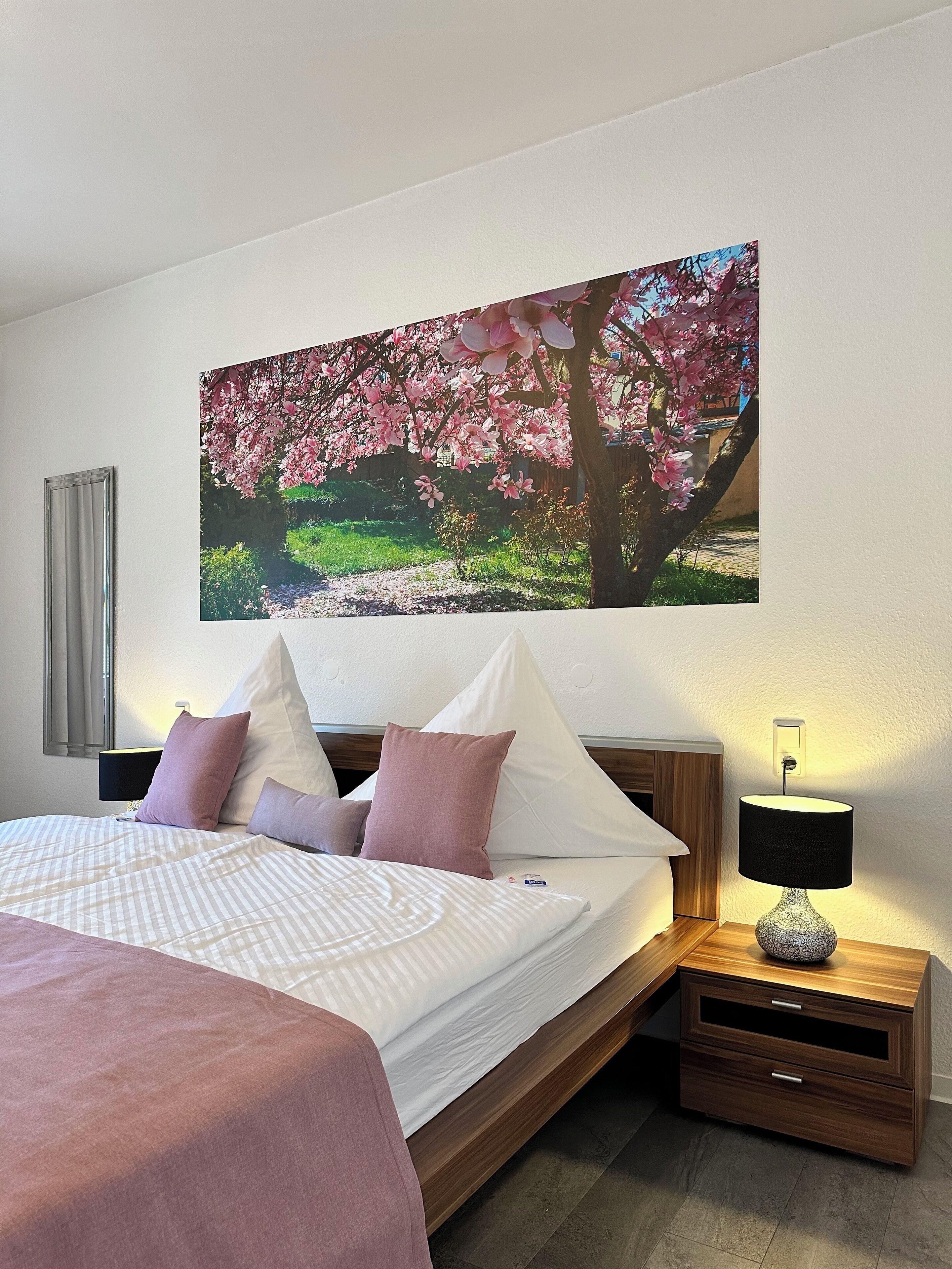 Quarto com cama grande, duas mesinhas de cabeceira e luminária na parede.