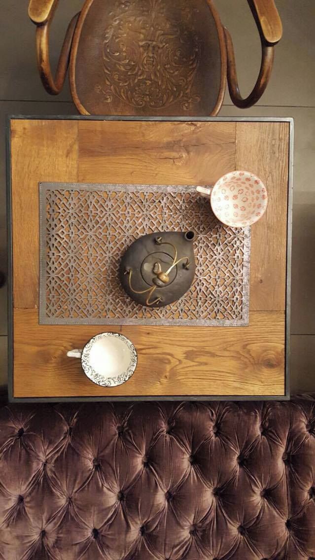 Uma mesa de madeira com uma bandeja de metal decorativa, um bule e uma xícara de chá.