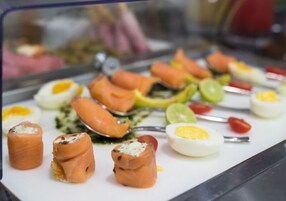 Diversos alimentos, incluindo salmão, ovos e vegetais em uma bandeja.