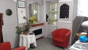 Um quarto com lareira, uma poltrona vermelha, uma mesa pequena com uma planta e uma janela com vista para o exterior.
