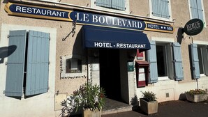 Um edifício com uma placa que diz "LE BOULEVARD HOTEL RESTAURANT" e "Logis Hotels".