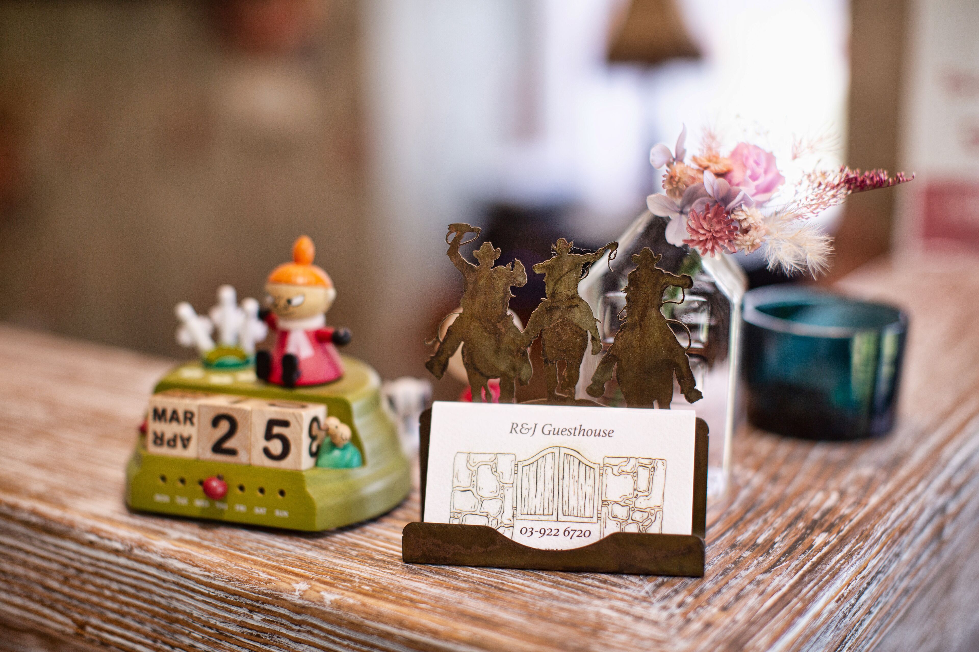 Uma mesa de madeira com um calendário, uma estatueta decorativa de cavalo e um cartão de visita.