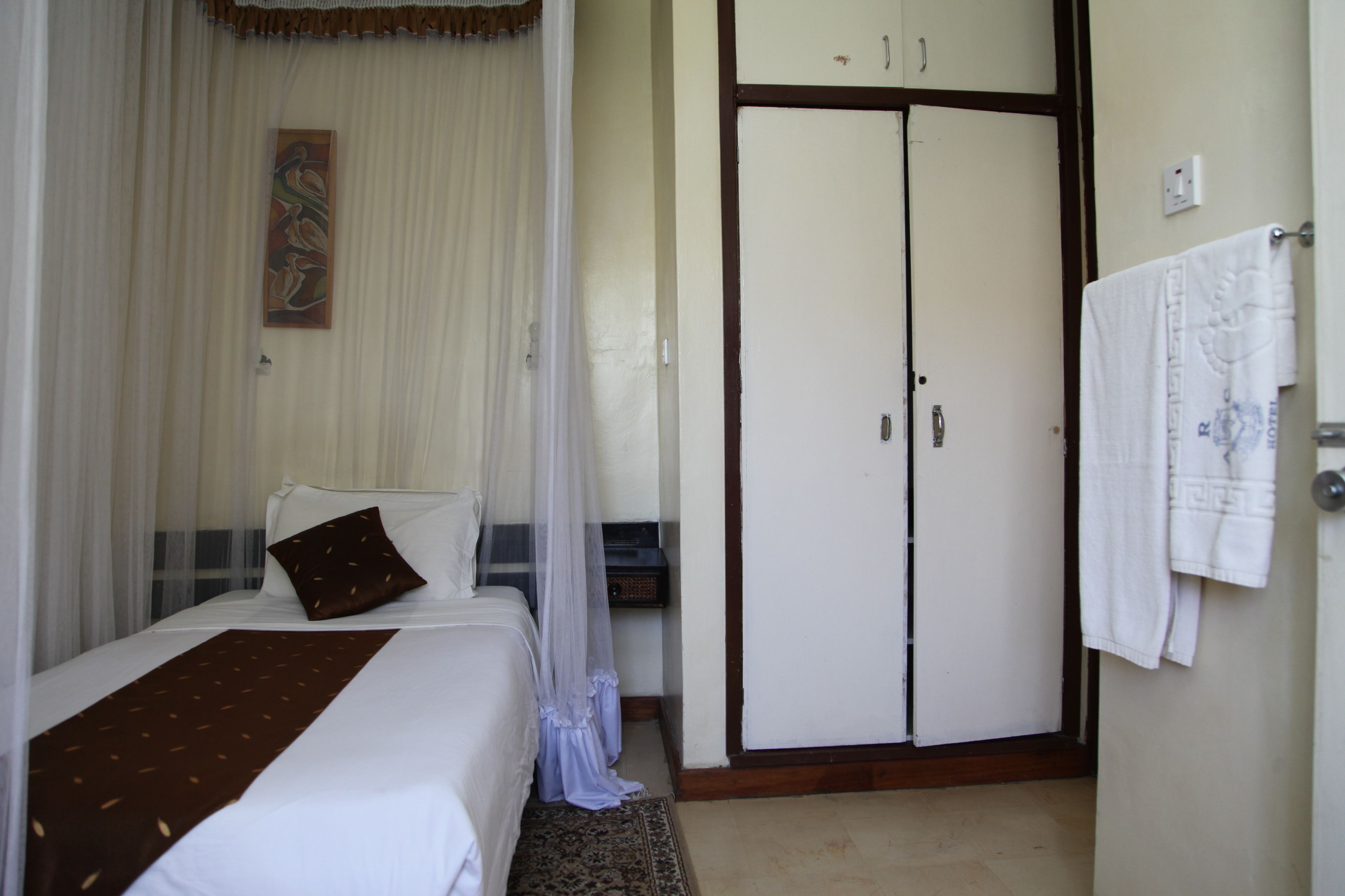 Quarto de hotel com cama, armário e banheiro.