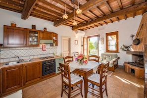 Uma cozinha rústica com armários de madeira, uma mesa de jantar com cadeiras e uma lareira.