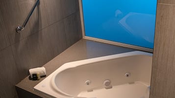 Uma casa de banho moderna com banheira, barra de apoio e dispensador de toalhas.