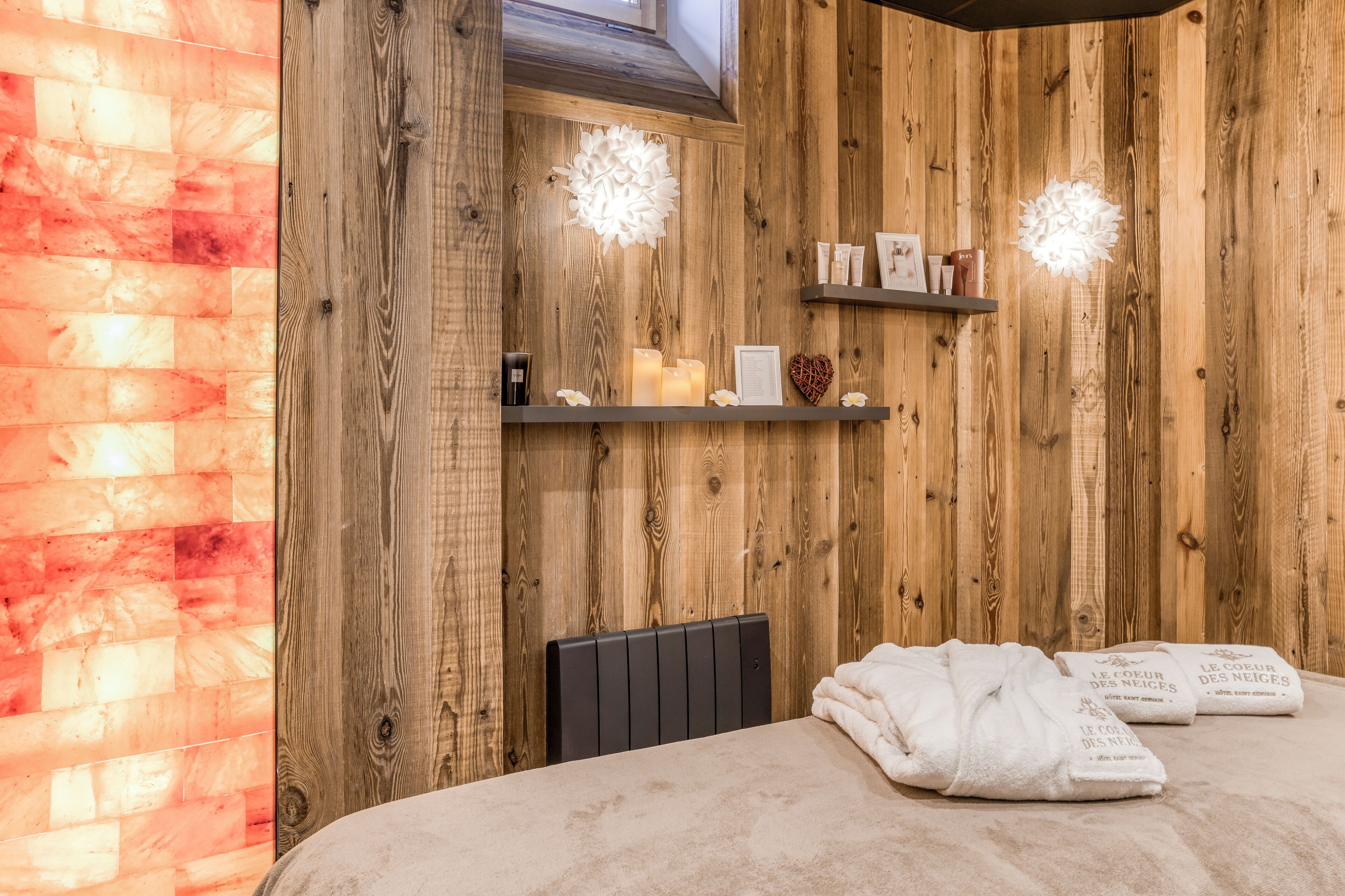 Quarto de madeira com uma cama, um radiador e estantes com produtos de higiene pessoal.