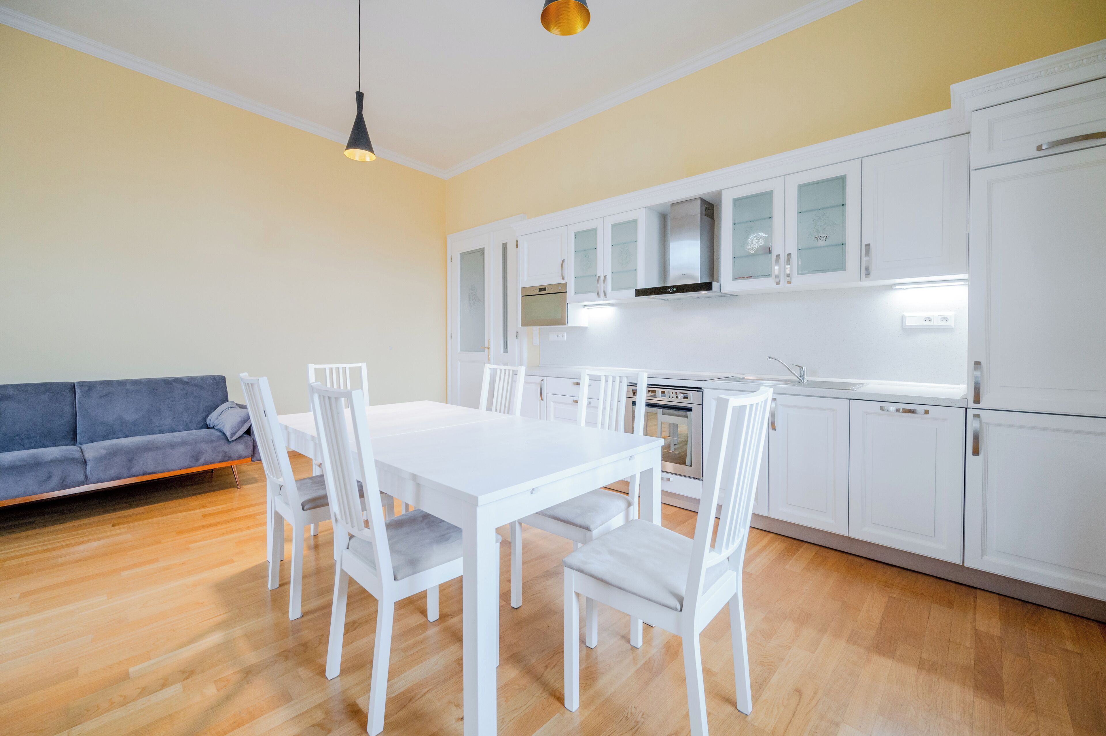Cozinha moderna com armários brancos e uma área de refeições com mesa e cadeiras brancas.