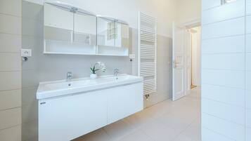 Casa de banho moderna com toucador branco, duas pias e um espelho grande.