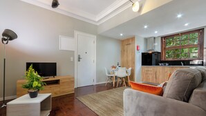 Uma sala de estar moderna com uma televisão de tela plana, uma planta em vaso e um sofá.