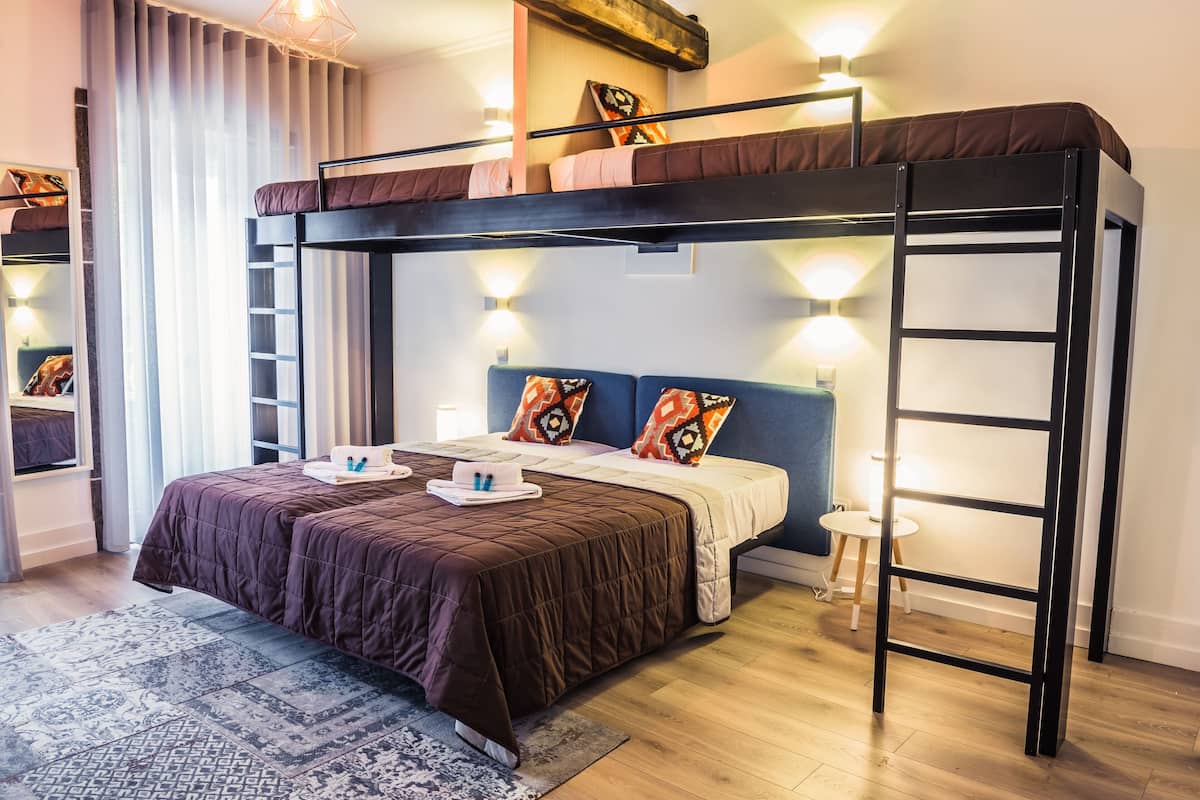 Quarto com beliches, mesinhas de cabeceira e um tapete estampado.