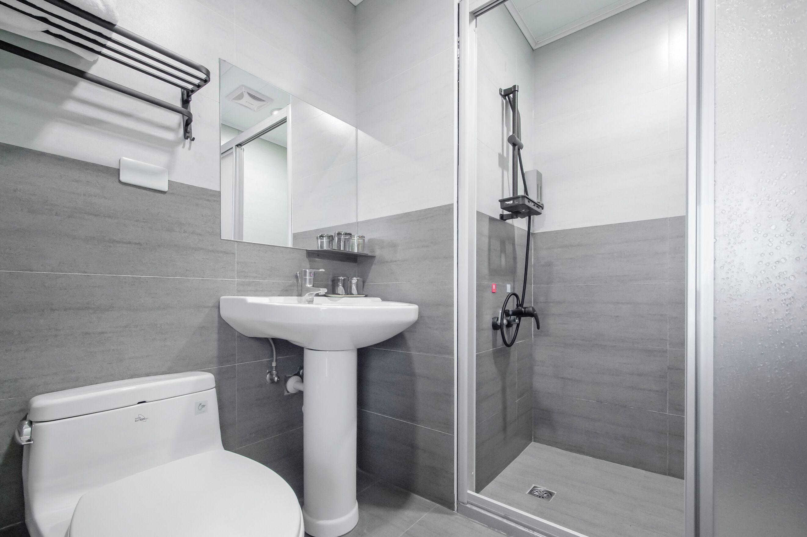 Um banheiro moderno com vaso sanitário, pia com coluna e chuveiro com box de vidro.