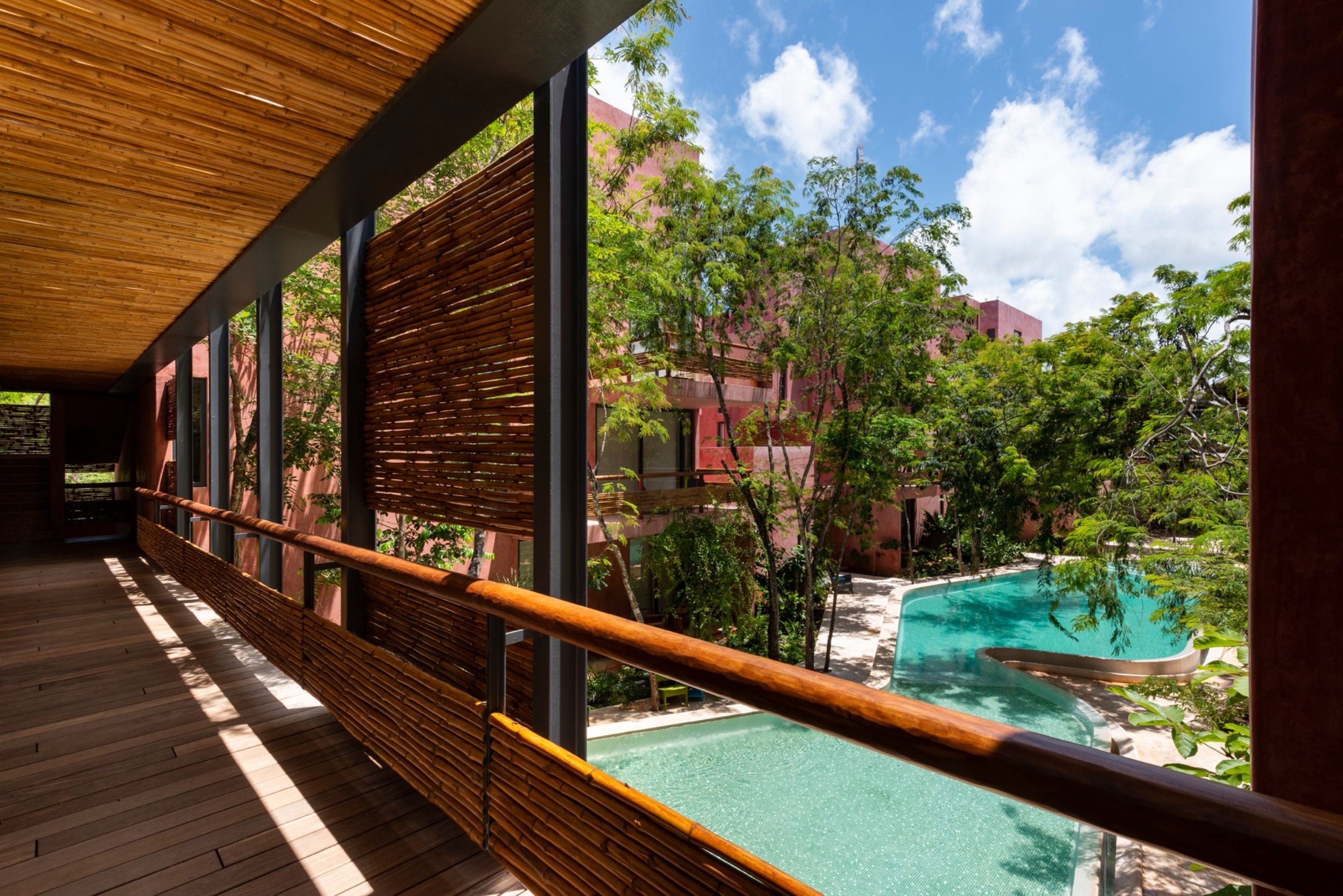 Um deck de madeira com vista para uma piscina e vegetação ao redor.