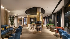 Um hall amplo com bar central, áreas de estar e uma grande planta.
