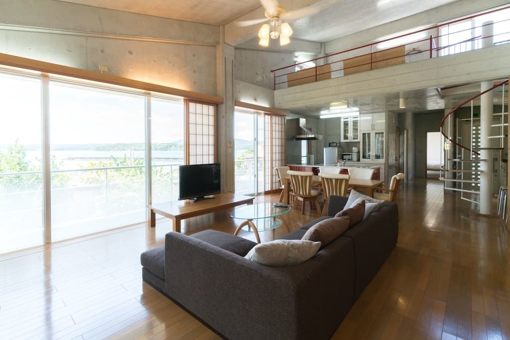 Uma sala de estar ampla com sofá, televisão e mesa de jantar.